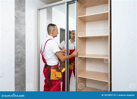 Furniture Assembling Professional Worker Installing Wardrobe At Living Room Of New House Stock