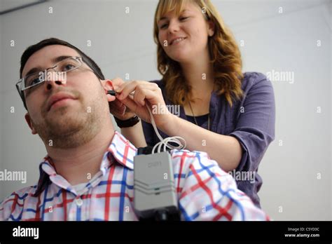 Close Up Of Audiology And Deafness Male Student Having Hearing Aid Inserted Into Ear By Female