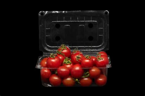 Premium Photo Small Tomatoes In Plastic Packaging On A Black Background