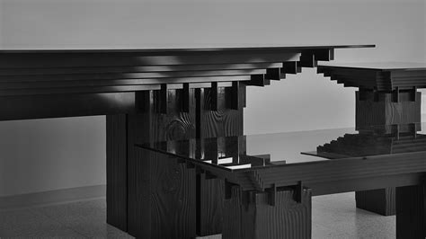 Gridded Steel Frames Slice Through Charred Timber Bases For Lin Tables