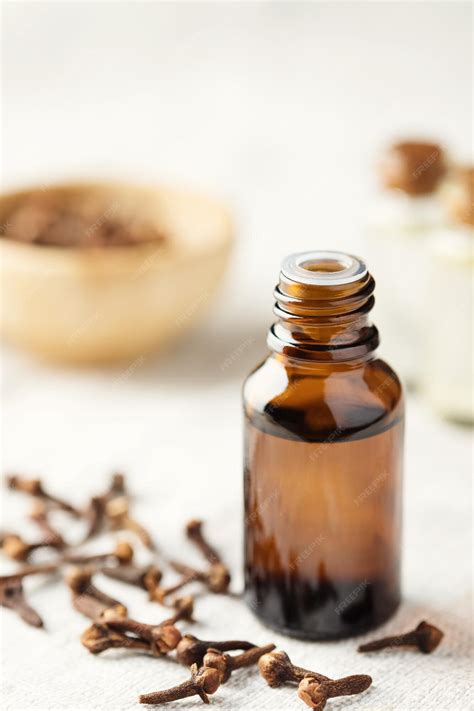 Premium Photo A Glass Bottle Of Clove Oil And A Clove On The Table