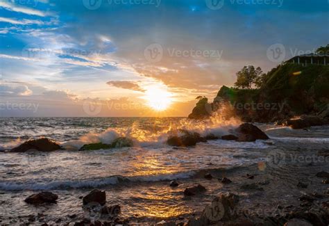 Splash Sea Waves On Rock Beach With Sunset Rain Clouds Sky With Light