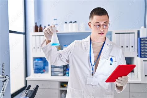 Young Hispanic Man Scientist Measuring Liquid Using Touchpad At