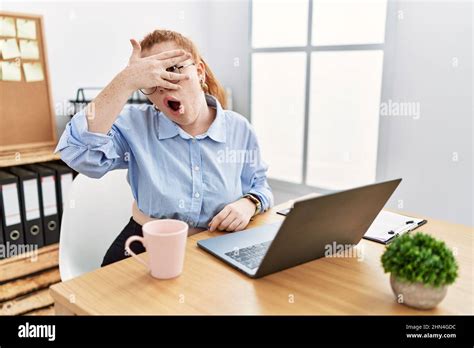 Young Redhead Woman Working At The Office Using Computer Laptop Peeking