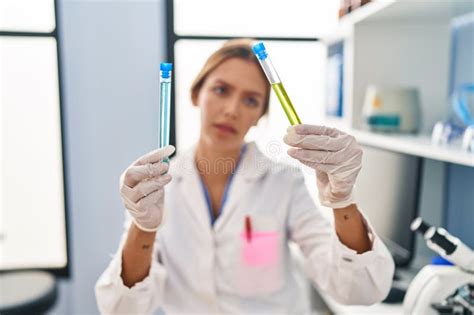 Young Hispanic Woman Scientist Holding Test Tubes At Laboratory Stock