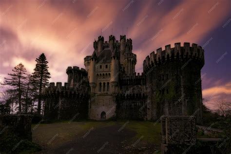 Night View Of The Butron Castle In Gatika Bizkaia With A Sky Covered In Red Clouds Premium Photo