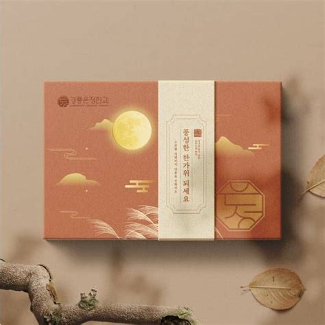 An Orange Box With Chinese Writing On It Sitting Next To A Tree Branch And Some Leaves