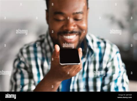Happy Black Man Using Voice Assistant Application On Phone Indoors