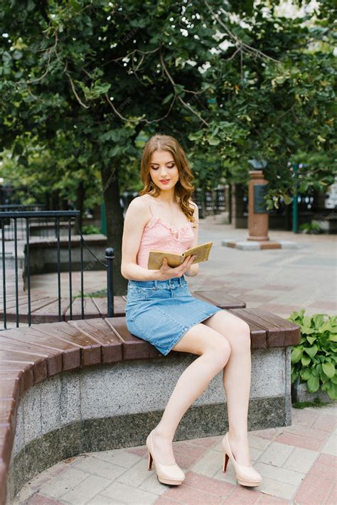 Premium Photo Girl In A Pink Top And Denim Skirt Reading A Book While