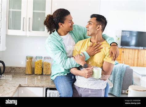 Biracial Man Embraces His Middle Eastern Partner In A Cozy Kitchen