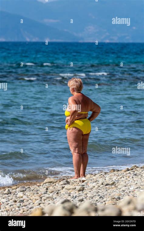 A Middle Aged Overweight Lady Wearing A Yellow Bikini Standing On The