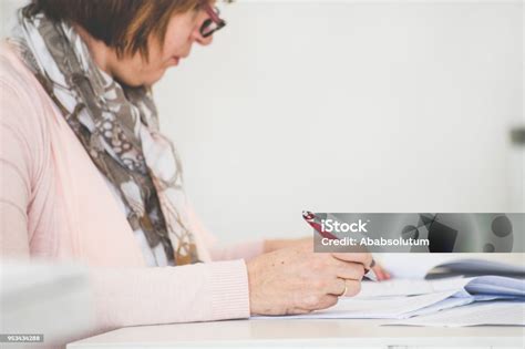 Mature Female Chemistry Teacher Correcting Test Papers In A High School