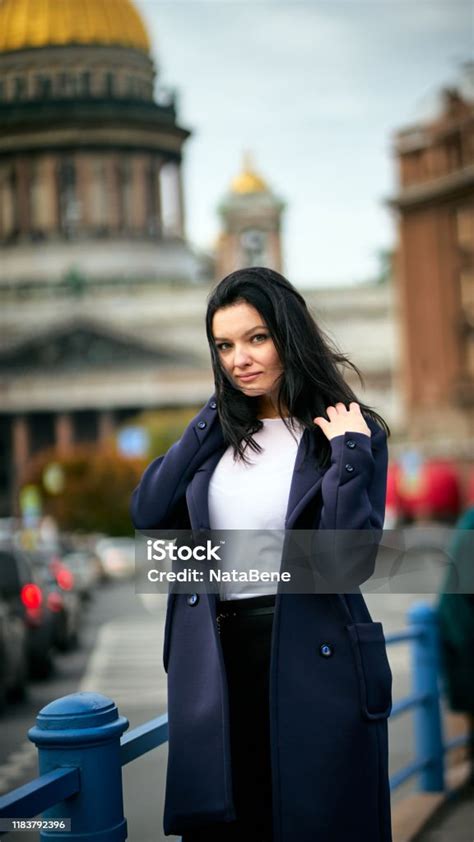 긴 어두운 머리를 가진 매력적인 사려 깊은 옷을 입은 여자는 유럽을 여행 상트 페테르부르크의 도심에 서 혼자 긴 어두운 머리 방황 사려 깊은 여자 가을에 대한 스톡 사진 및