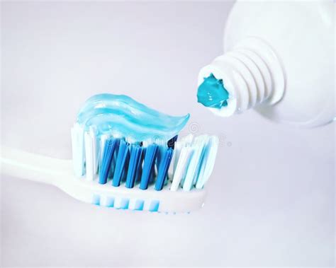 Applying Toothpaste To A Brush On A Light Background Close Up Blue