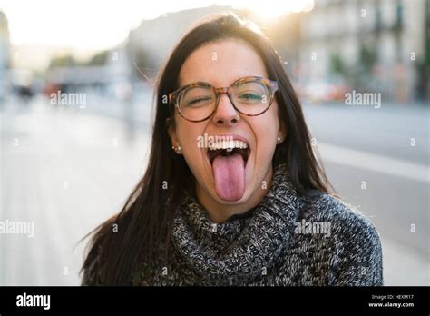 Portrait Of Happy Young Woman With Glasses Sticking Her Tongue Out