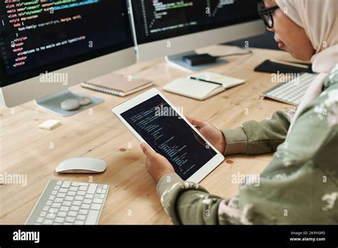 Close Up Of Young Muslim Female Programmer Looking Through Coded Data On Tablet Screen While
