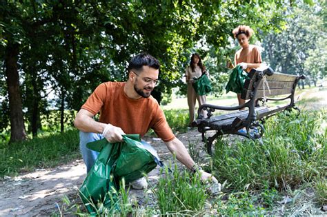 젊은 자원봉사자들이 함께 공원을 청소하고 쓰레기를 수거하고 쓰레기 봉투를 들고 있다 책임감 있는 부모와 친구들은 아이들이 자연 속에서 놀기 전에 쓰레기로 공원을 청소합니다