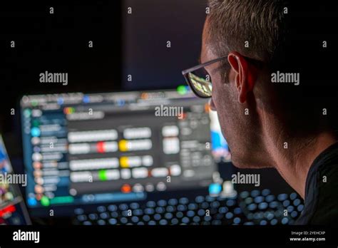 Cybersecurity Professional Analyzing Data on Multiple Screens in a Low-Light Workspace for ...
