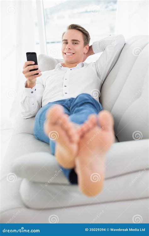 Entspannter Junger Mann Der Auf Sofa Und Versenden Von Sms Nachrichten