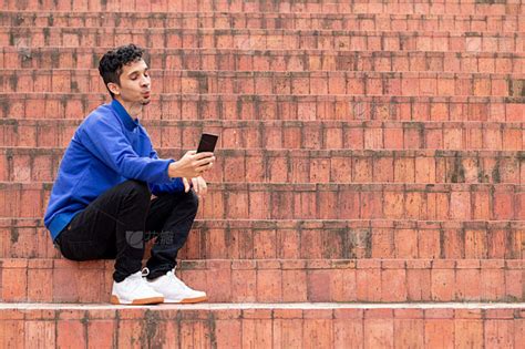 一名表情滑稽的男子在自拍。橙色和蓝色。橙色楼梯上穿着蓝色连身衣的人。广告的商业概念。