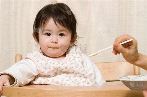 一个婴儿在一个木制的高脚椅被喂婴儿食品的特写素材 花瓣网