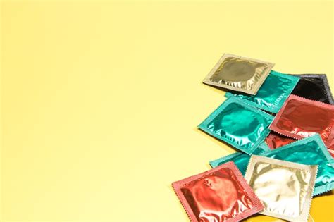 Preservativos coloridos de ângulo alto no fundo amarelo Foto Grátis