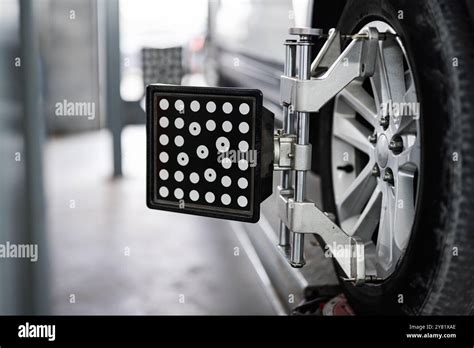 Close-up of a car wheel alignment process using advanced equipment in an automotive repair shop ...