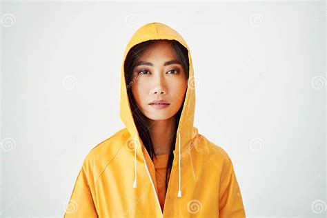 Serious Asian Girl Dressed In Bright Yellow Raincoat Posing With Hood