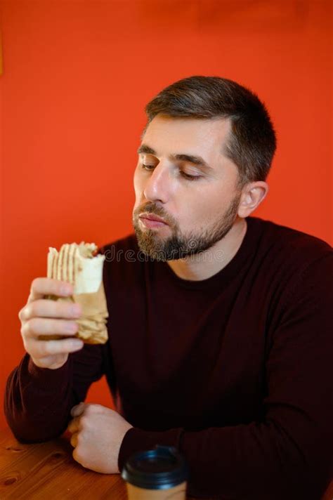 A Man With A Beard Eats Shawarma A Quick Tasty And Healthy Snack At A Fast Food Restaurant