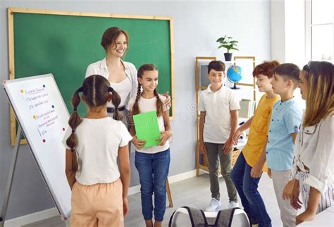 Friendly Teacher And Her Students Are Standing Around White Board