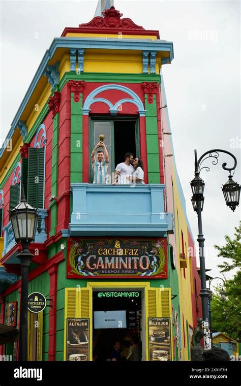 Couple Pose Next To A Lionel Messi Model On A Balcony On A Colorful