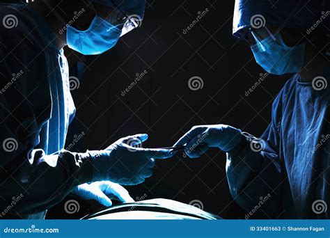 Two Surgeons Working And Passing Surgical Equipment In The Operating