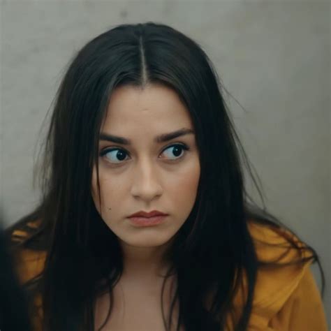 A Woman With Long Black Hair And Blue Eyes Looks At The Camera While