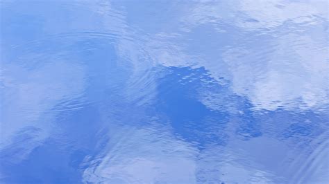 Small Ripples On The Surface Of The Lake With A Reflection Of The Blue Sky And White Clouds