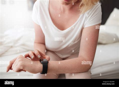 Closeup Shot Of Caucasian Female Checking Time On Her Wrist Watch While Sitting On Bed At Home