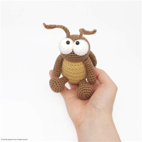 A Hand Holding A Small Crocheted Brown And White Stuffed Animal With