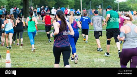 Rear View Of Male And Female Runners Racing A 10k On A Grass Field At