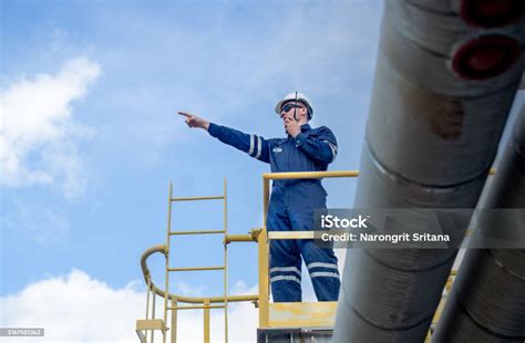 공장 엔지니어 또는 기술자 노동자 남자는 워키 토키를 사용하여 동료에게 연락하고 직장에서 석유 화학 가스의 파이프 라인을 통해 높은 상태에 서서 앞으로 가리 킵니다 30