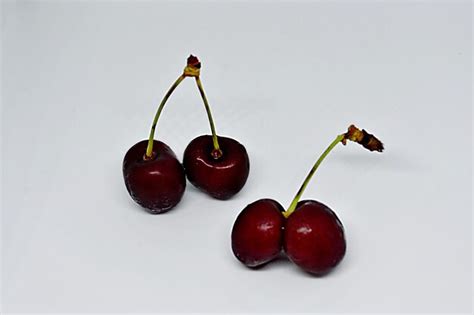 Premium Photo Two And Double Cherries Against White Background