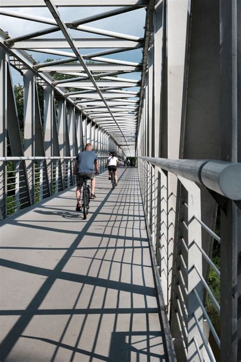 Cyclists Pass Through A Modern White Overhead Passage In Summer Stock