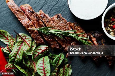 얇게 썬 구운 스테이크 중간 희귀 야채와 함께 블랙 커팅 보드에 제공됩니다 Steakhouse에 대한 스톡 사진 및 기타 이미지