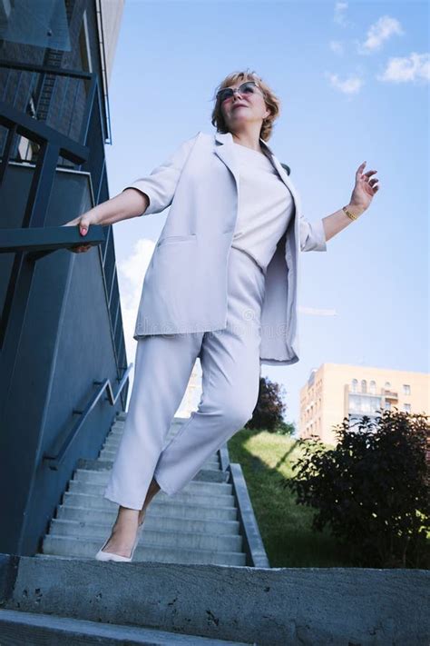 Aged Woman On A Walk In The City On A Summer Day Walks Up The Stairs