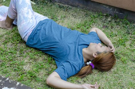 Young Asian Woman Fainting On Grass In Summer Because Outdoors Of Hot