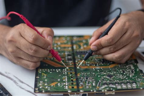 Technician Using Tool To Measure Circuit Board Check And Repair Stock