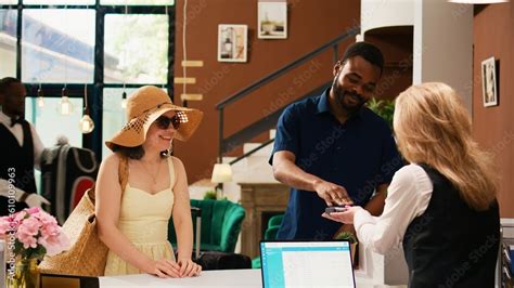 Couple Paying Room Accommodation At Check In Making Payment At Pos