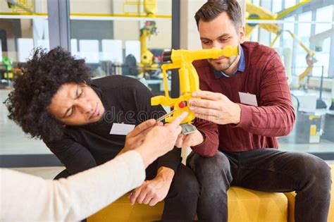 Engineers Examining Robotic Arm Model In Industrial Training Session