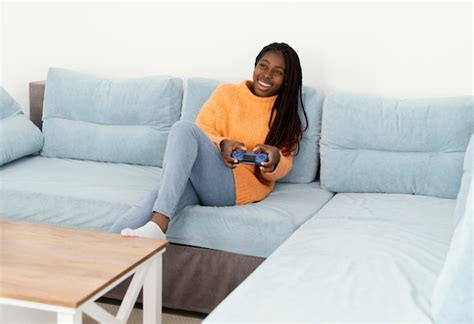 Free Photo Smiley Girl Playing Videogame On Couch