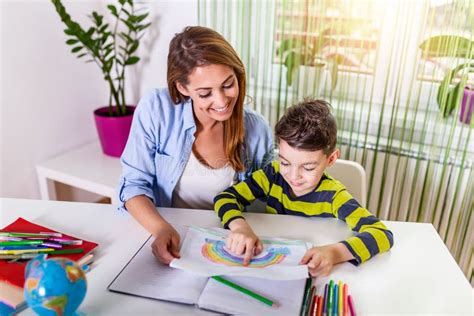 Young Boy Doing His School Homework With His Mother At Home He Is