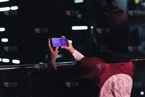 女孩拿着智能手机和网络购物设备在夜晚的霓虹灯街道上的背影，未来概念的城市素材 花瓣网