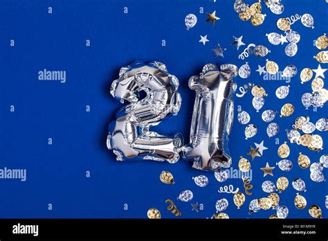 Silver foil number 21 balloon on a blue background with glitter ...